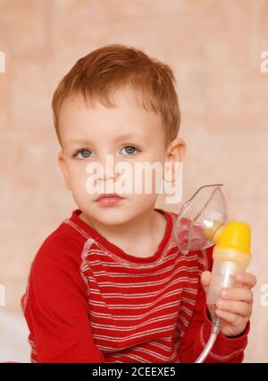 Cute baby boy makes inhalation with a nebulizer equipment. Sick child ...