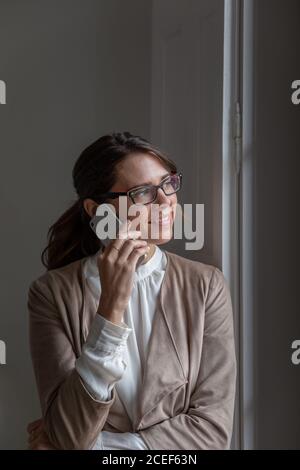 Young woman talking on mobile phone while decorating house with flower ...