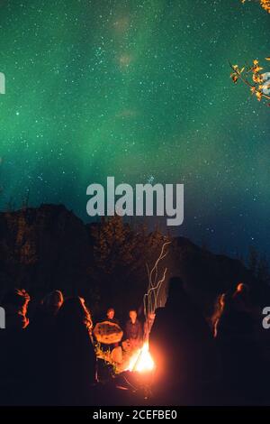 Group of people gathering around fire in woods Stock Photo - Alamy