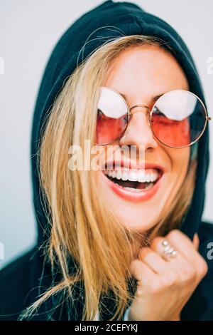 Young woman with sunglasses smiling, looking up while exiting red car ...