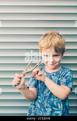 Blonde boy playing with a slingshot Stock Photo - Alamy