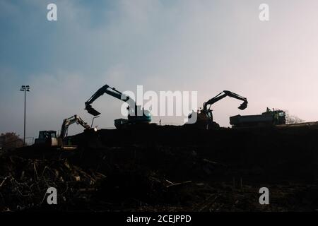 Diggers excavating land and freighting soil on trucks on blue sky ...