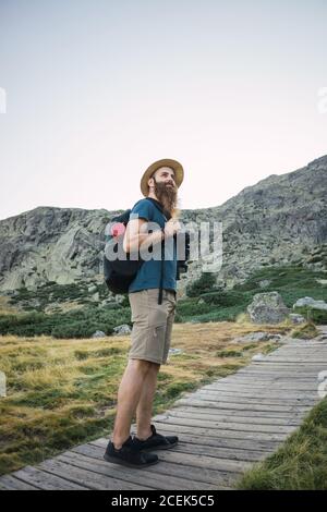 Young handsome man with beard standing with longboard on the street ...
