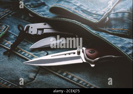 two stainless steel folding knifes over denim jacket Stock Photo - Alamy