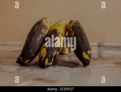 Mouldy yellow banana fruit closeup on a blue kitchen plate showing ...