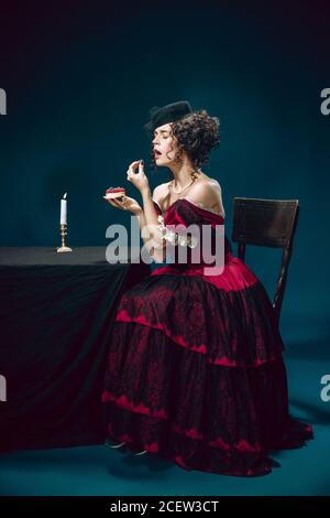 Diet and sweets. Young woman as Anna Karenina isolated on dark blue ...