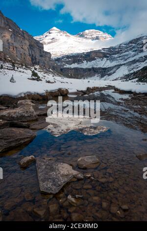 The vertical view of a valley with snow-covered rocky formations on a ...