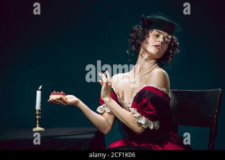 Diet and sweets. Young woman as Anna Karenina isolated on dark blue ...