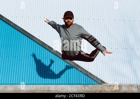barefoot guy in stylish outfit performing flip near wall of modern ...