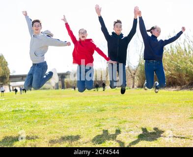 Four joyful teens jump on a spring lawn Stock Photo - Alamy