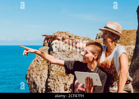 Side view of touristic women exploring sightings at rocky coast with ...