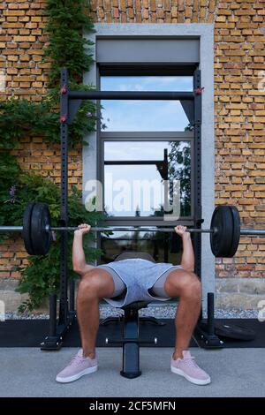 Powerful anonymous male athlete lifting heavy barbell with weights ...