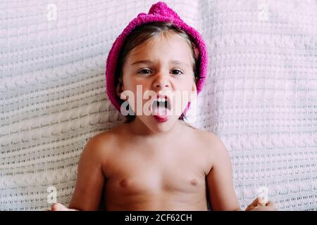 Kid in pink turban without clothes concentrated on playing with plastic ...