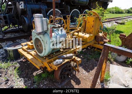 A yellow antique railway spike driver sits on the grounds of the Fort ...