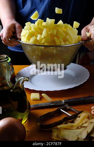 Crop female chef filtering fresh raw pieces of potatoes with sieve ...