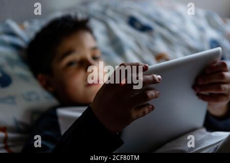 Delighted boy using tablet in bedroom during weekend Stock Photo - Alamy