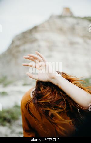 Hand of anonymous female holding stylish sandals in hole in blue paper ...