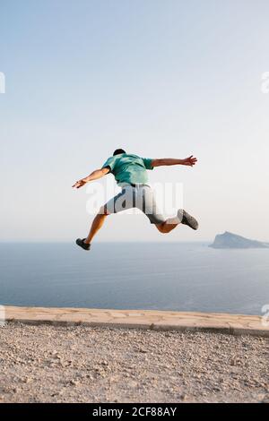 Low angle back view of unrecognizable carefree male traveler in stylish ...