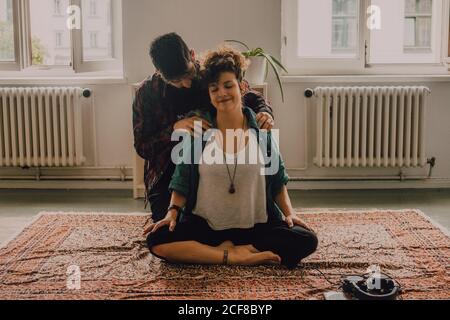man in casual outfit massaging back of relaxed Woman sitting in lotus ...