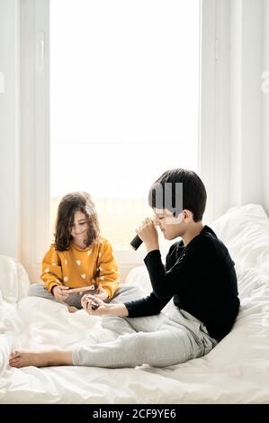 Siblings relaxing on bed in bedroom Stock Photo - Alamy