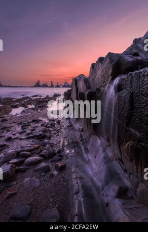 Background of a red rough cliff in the blue ocean Stock Photo - Alamy