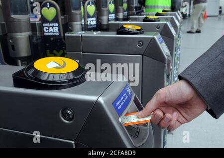 Hand putting train ticket into a TFL stations ticket barrier in Greater ...