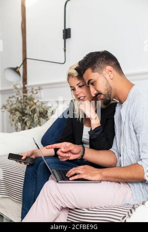 Girlfriend and boyfriend browsing smartphone and laptop at home ...