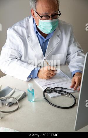 General practitioner wearing medical mask and protective gloves working ...