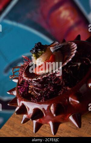 Served delicatessen in small oyster shell on modern shiny ceramic ...