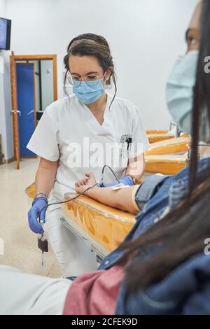 Crop female medical specialist in protective uniform, latex gloves and ...