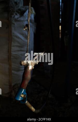 Professional sheep shearing razor hanging on rope in dark barn on farm ...