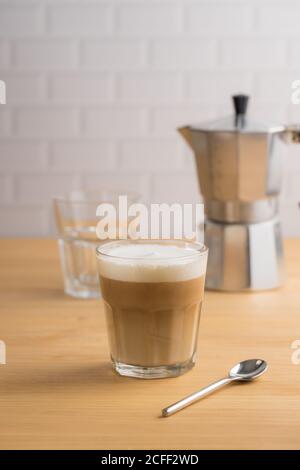 Delicious coffee with milk in glass and beans on brown background ...