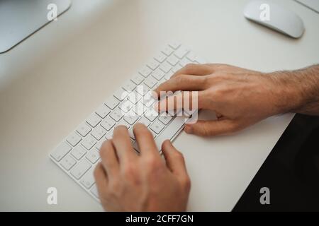 Cropped anonymous male freelancer on table using laptop and working on ...