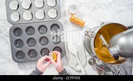 Flat lay. Scooping pumpkin spice cupcake batter with batter scoop into ...