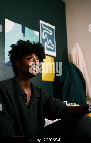 From below young female with curly hair in casual clothes smiling and ...