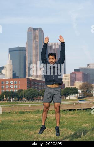 Male sportsman stretching hand while jumping on walkway Stock Photo - Alamy
