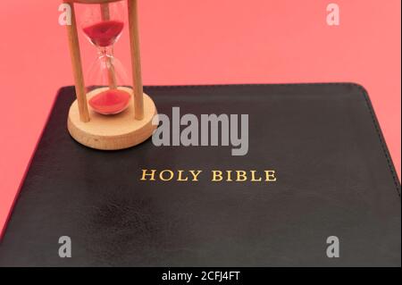 Red sand hourglass on top of Holy Bible opened in Revelation of Jesus ...