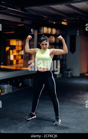 Sporty woman flexing muscles with energy to show off her biceps and ...