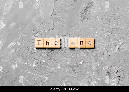 The end word written on wood block. The end text on wooden table for ...