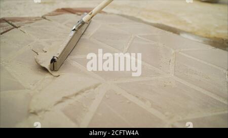 poorly laid pavement tiles on a walkway in the park. Worker makes ...