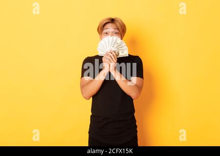 Excited lucky blond asian guy rejoicing from winning cash, holding ...