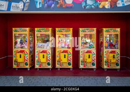Arcade with claw crane game machines and child playing with coin pusher ...