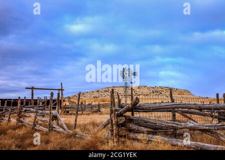 A windmill behind an old wooden pole fence cattle corral and loading ...