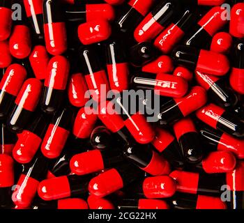 Red-black antibiotic capsule pills spread out of plastic drug bottle on ...