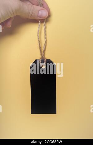 Hand holding a white tag with string Stock Photo - Alamy