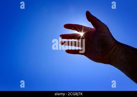 Hand reaching up towards heaven seeking help with sunstar sunshine ...