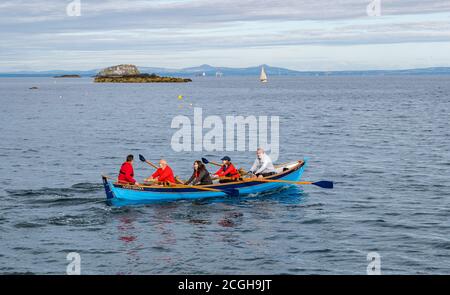Coastal rowing crew in a St Ayle's wooden skiff wearing face masks in ...