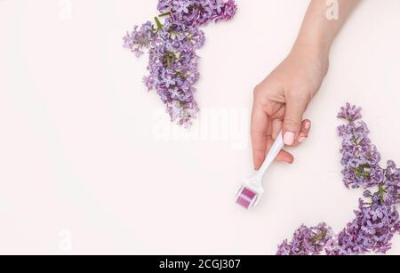 Mesoroller and lilac flowers on a white background. Concept of skin ...