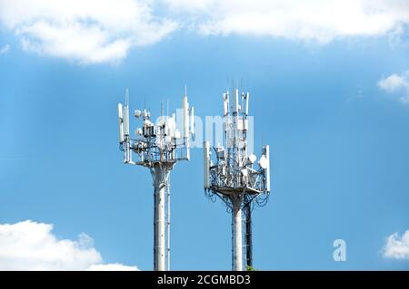 Two telecommunication towers with radio modules and antennas against a background of blue sky ...