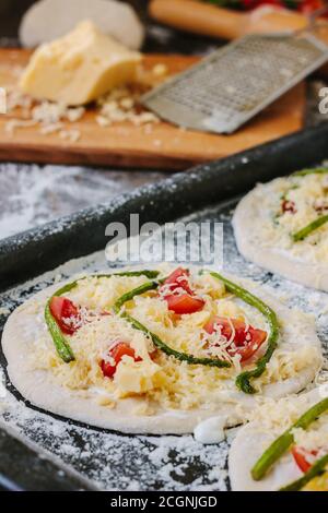 Cooking process of mini pizza with asparagus, tomatoes and cheese Stock ...
